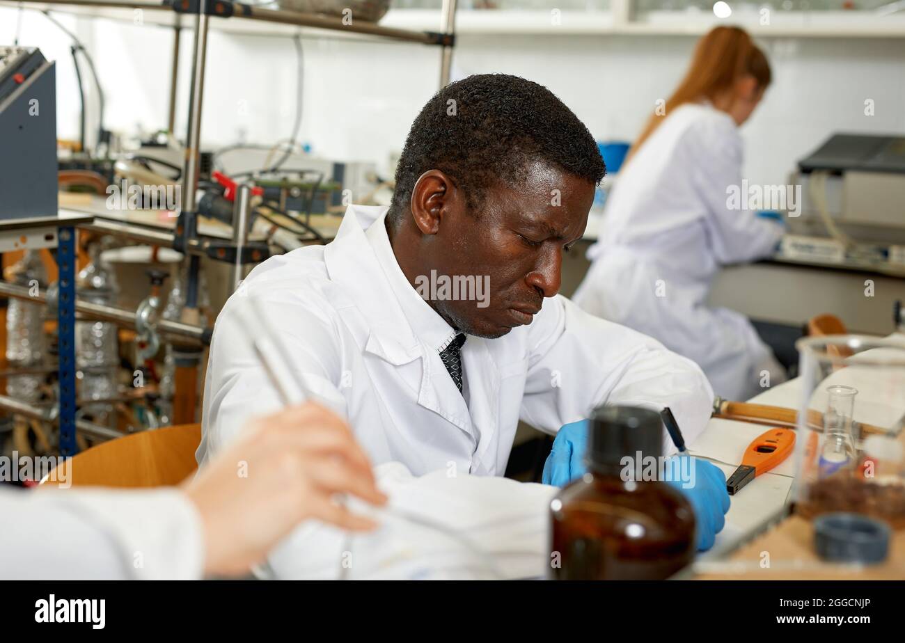 Experienced female scientist writing report after chemical experiment ...