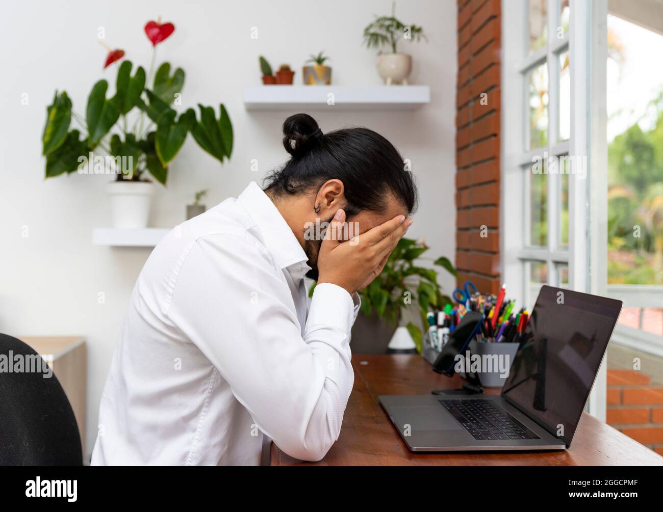 very stressed young man in front of the laptop with his hands hiding ...