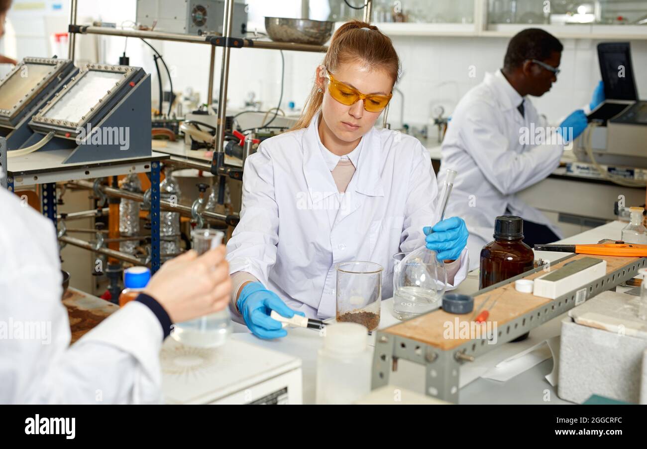 Woman lab technicians in glasses working with reagents and test tubes ...