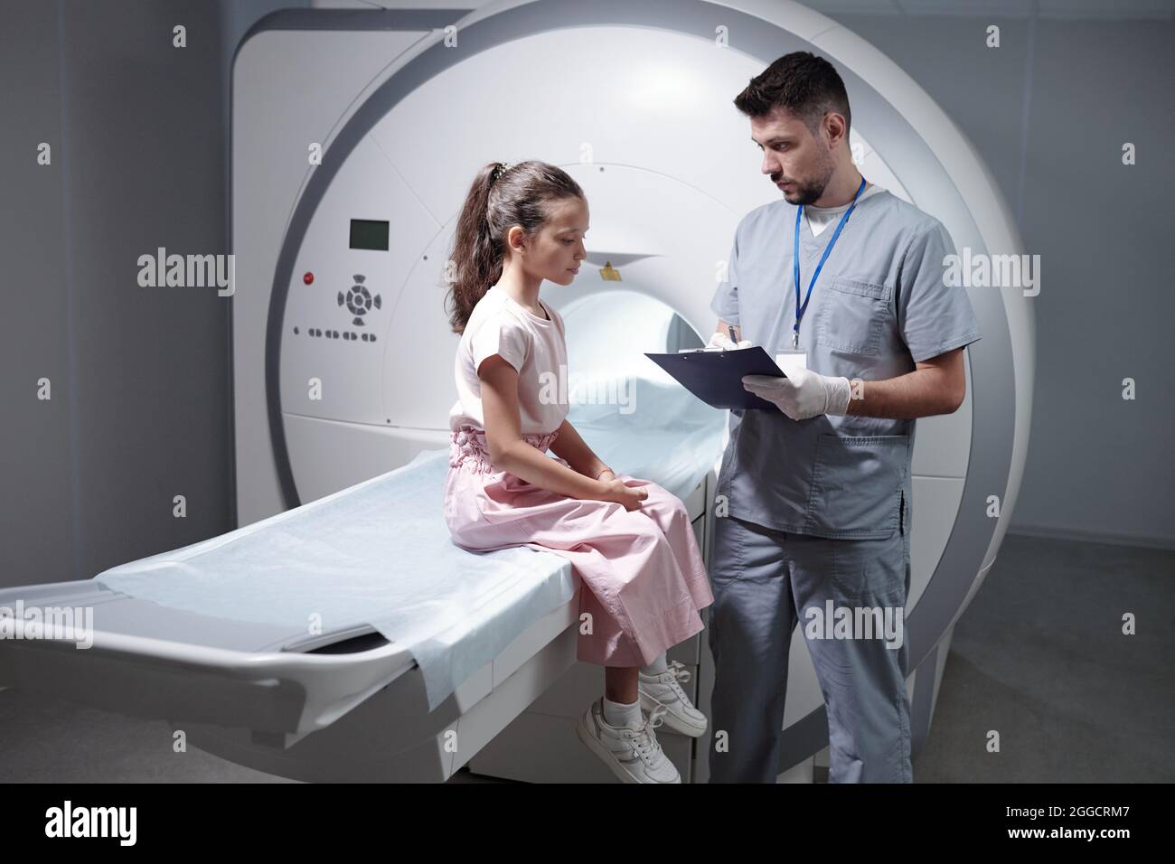 Serious radiologist making prescription to little girl after MRI scan ...