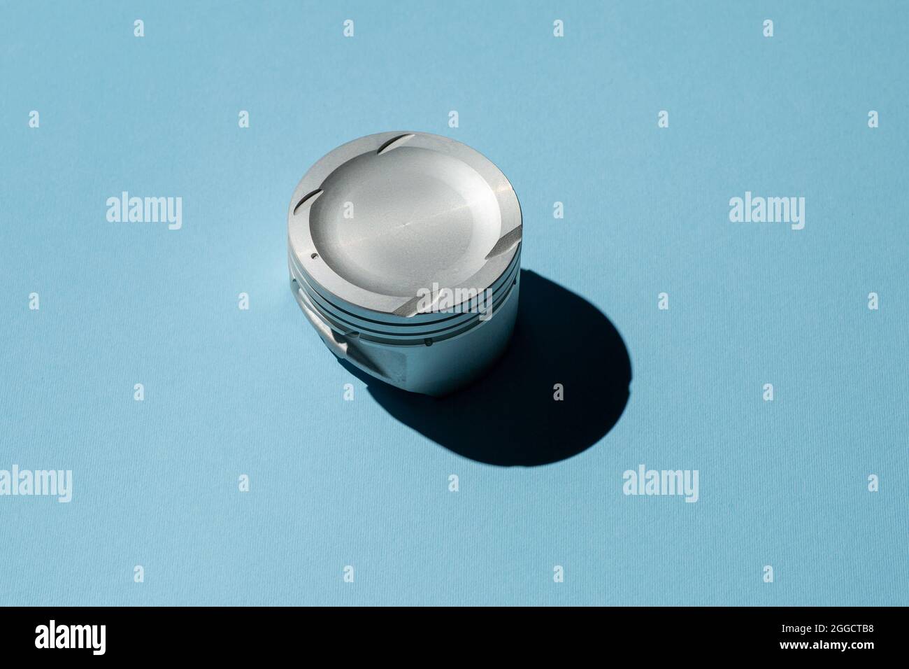Piston from a car engine on the blue background with copy space ...