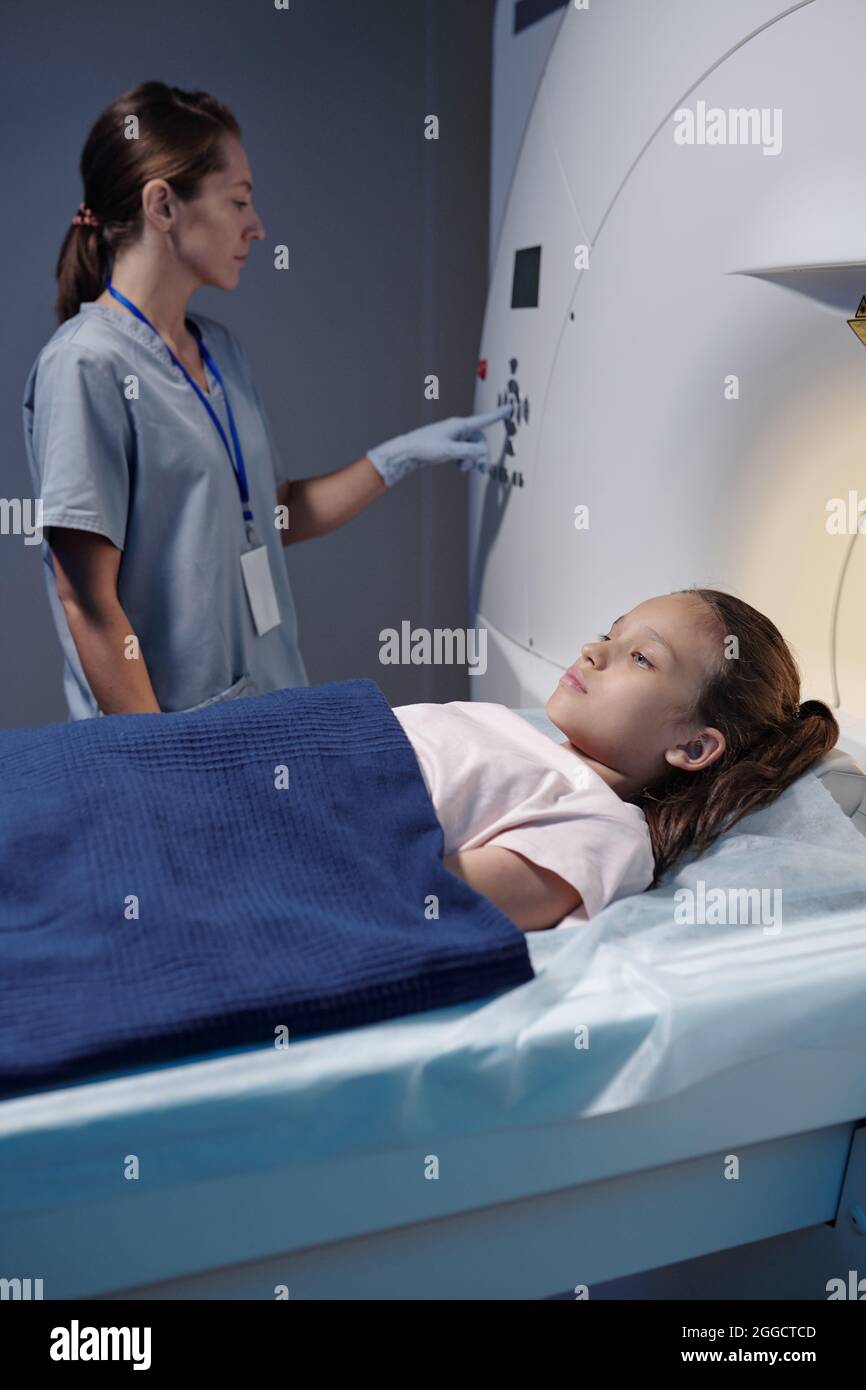 Female doctor pushing button on control panel while little patient ...