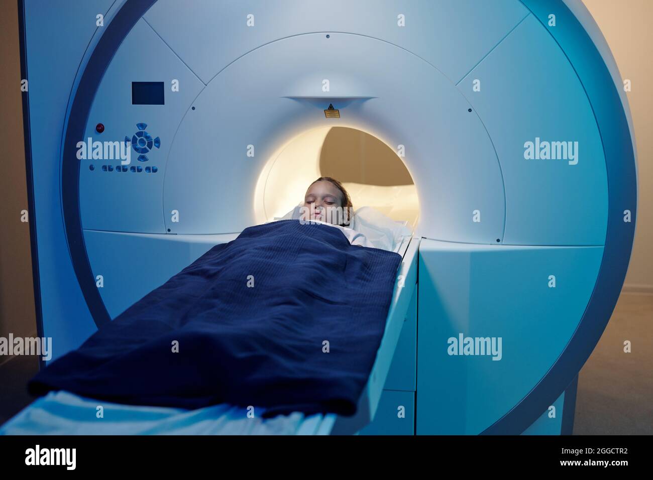 Little girl lying on long medical table while moving into mri scan ...