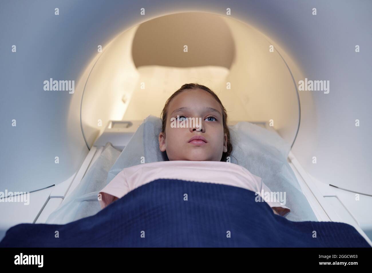 Contemporary little girl undergoing mri scan procedure in clinics or ...