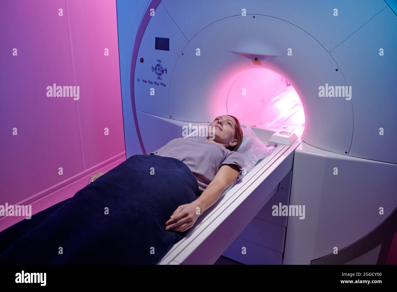 Young female patient lying on long table of mri scan machine while ...