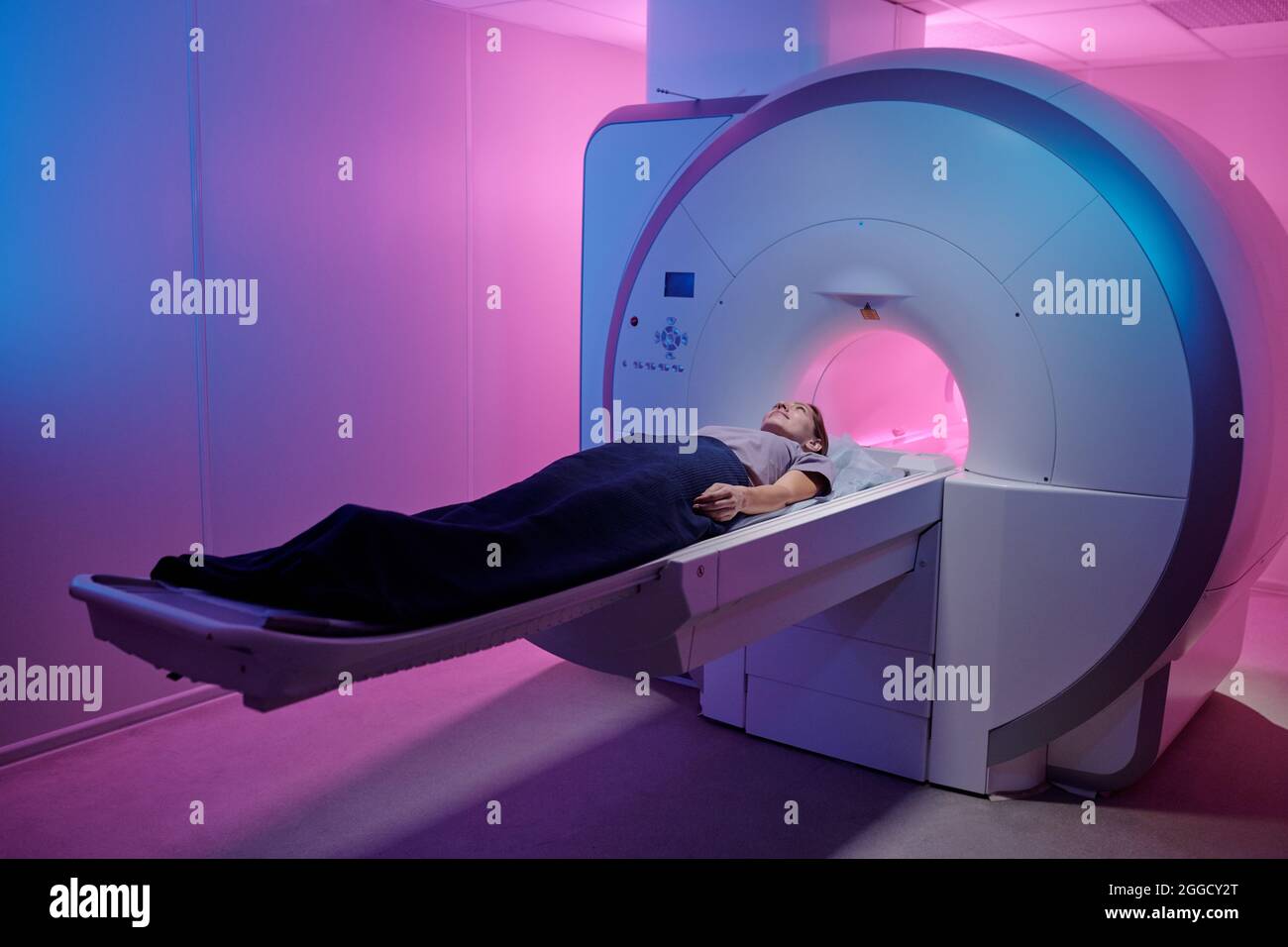 Young woman lying on long table of medical equipment before undergoing ...