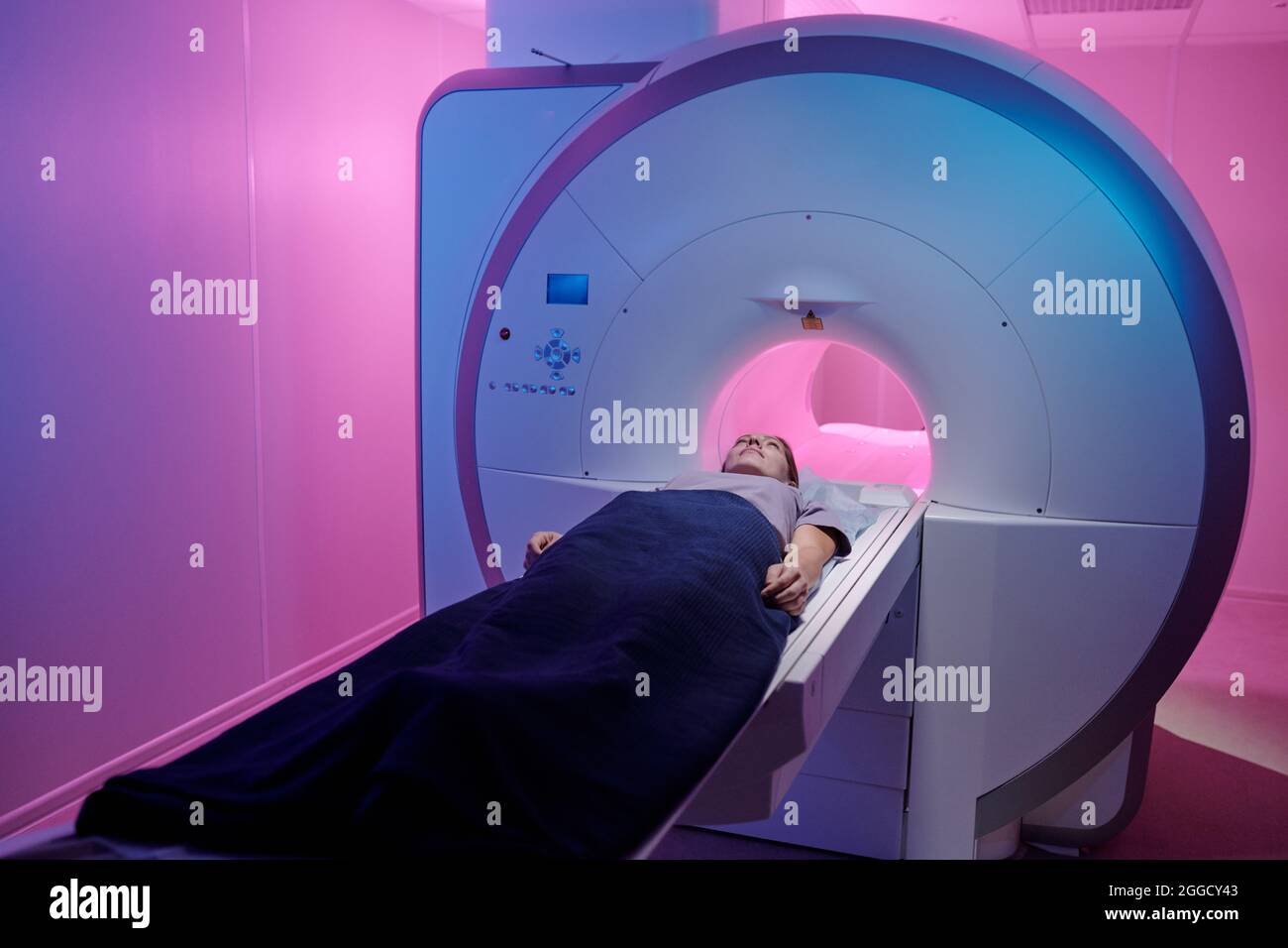 Young sick woman undergoing medical procedure on mri scan machine in ...