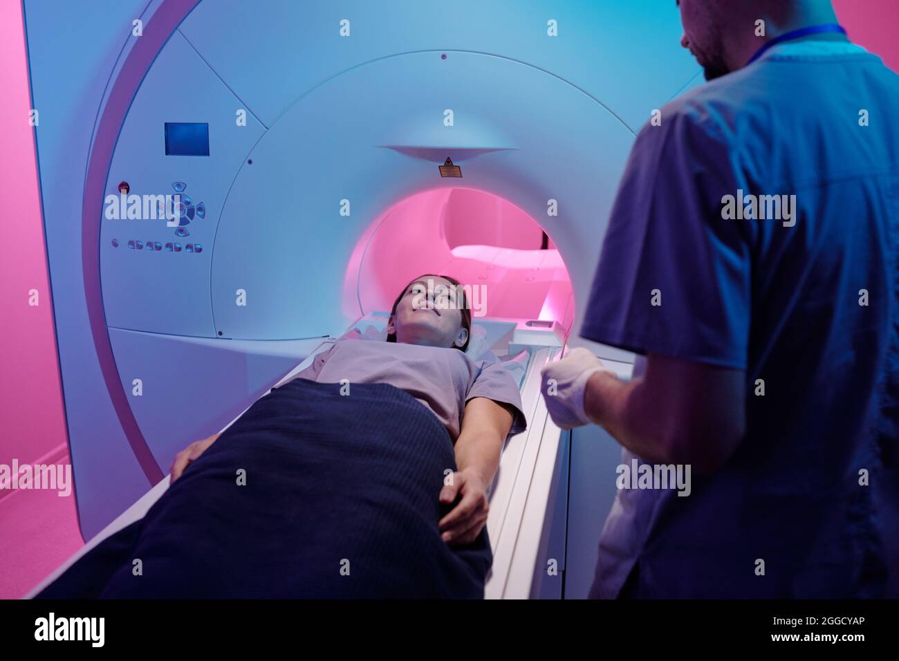 Young female patient looking at radiographer before medical diagnostics ...
