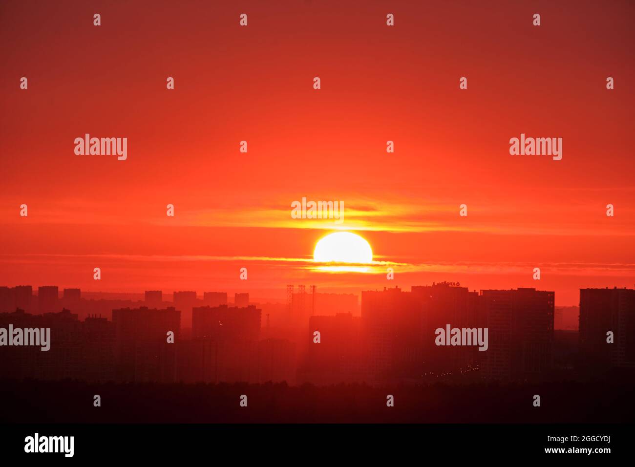 The big red sun sets behind the roofs of houses at sunset, timelapse ...
