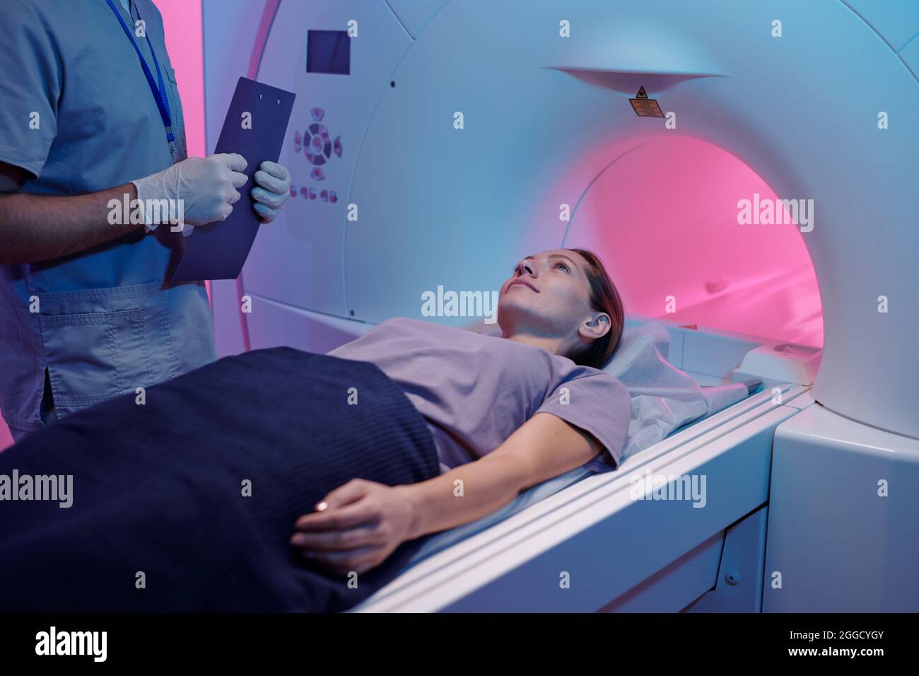 Young female lying on long table of mri scan machine while doctor ...