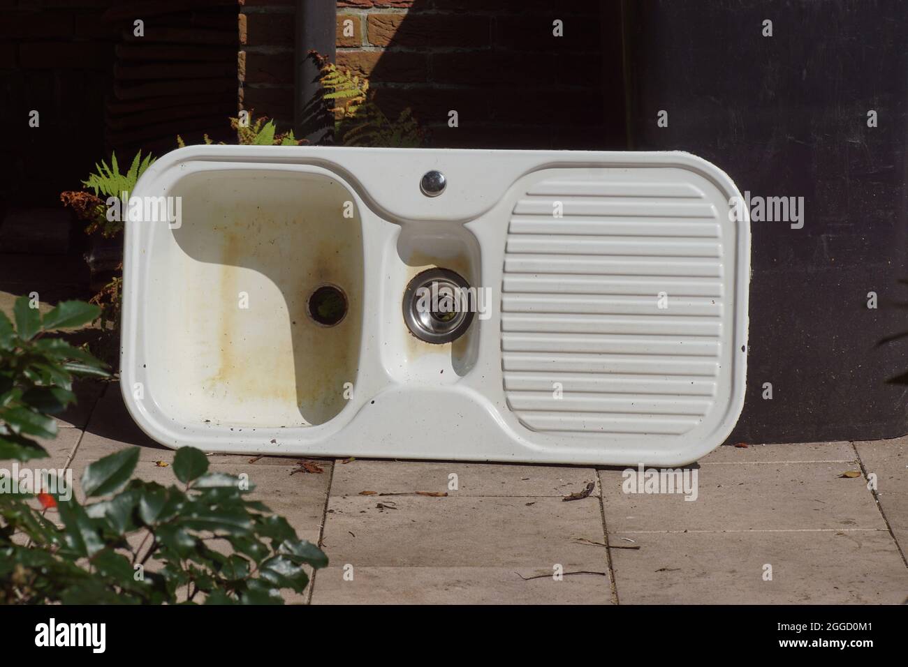 Old, discarded, white enamelled, iron sink for a kitchen counter ...