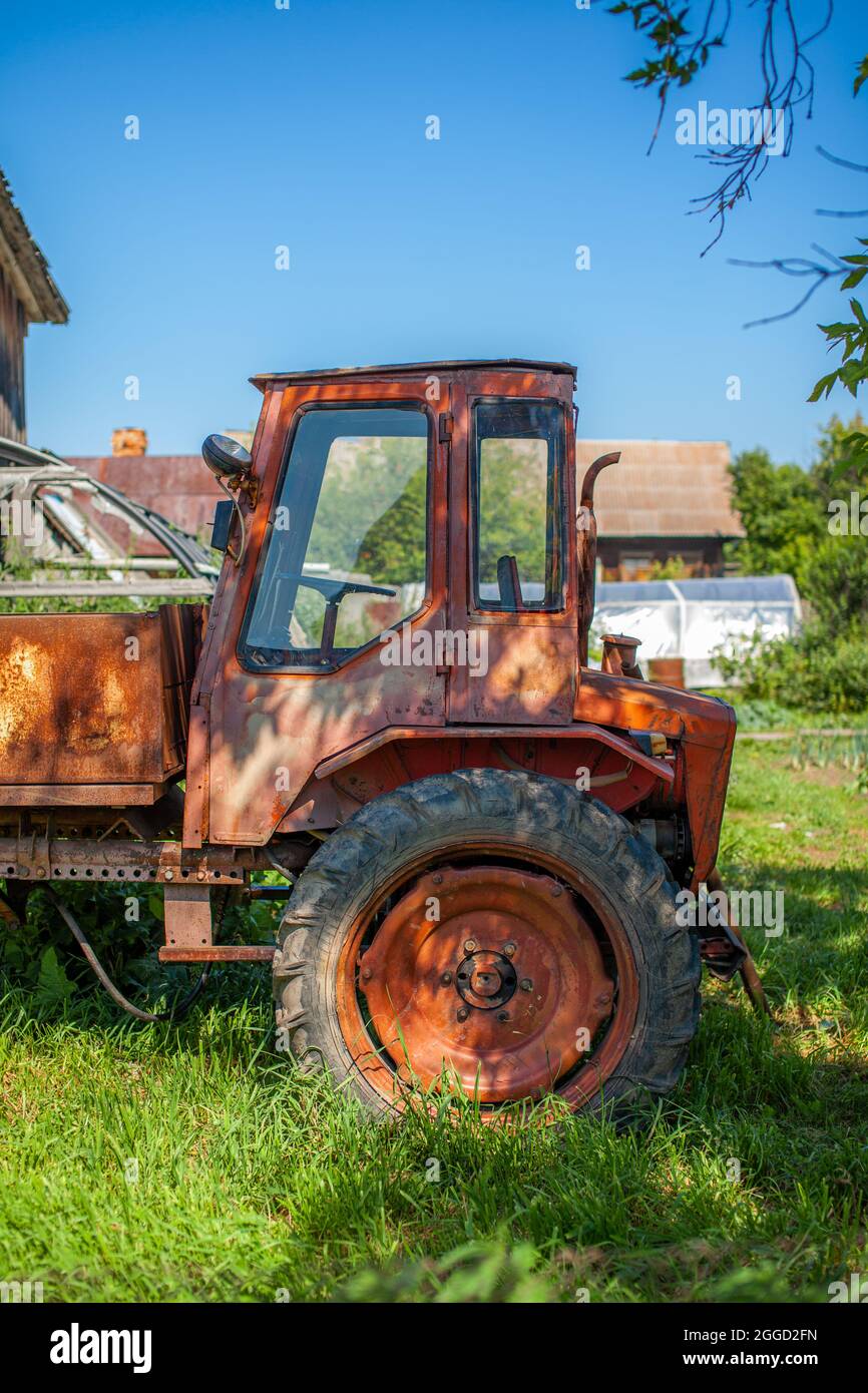 An old rusty tractor stands near the barn. A red old tractor for ...