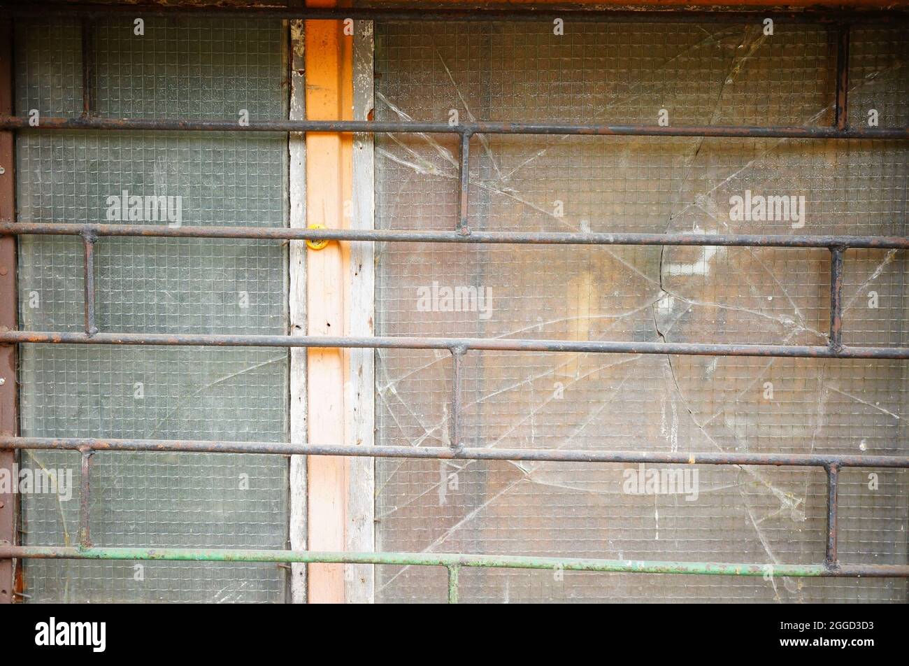 Broken glass of an old window behind rusty grills Stock Photo - Alamy