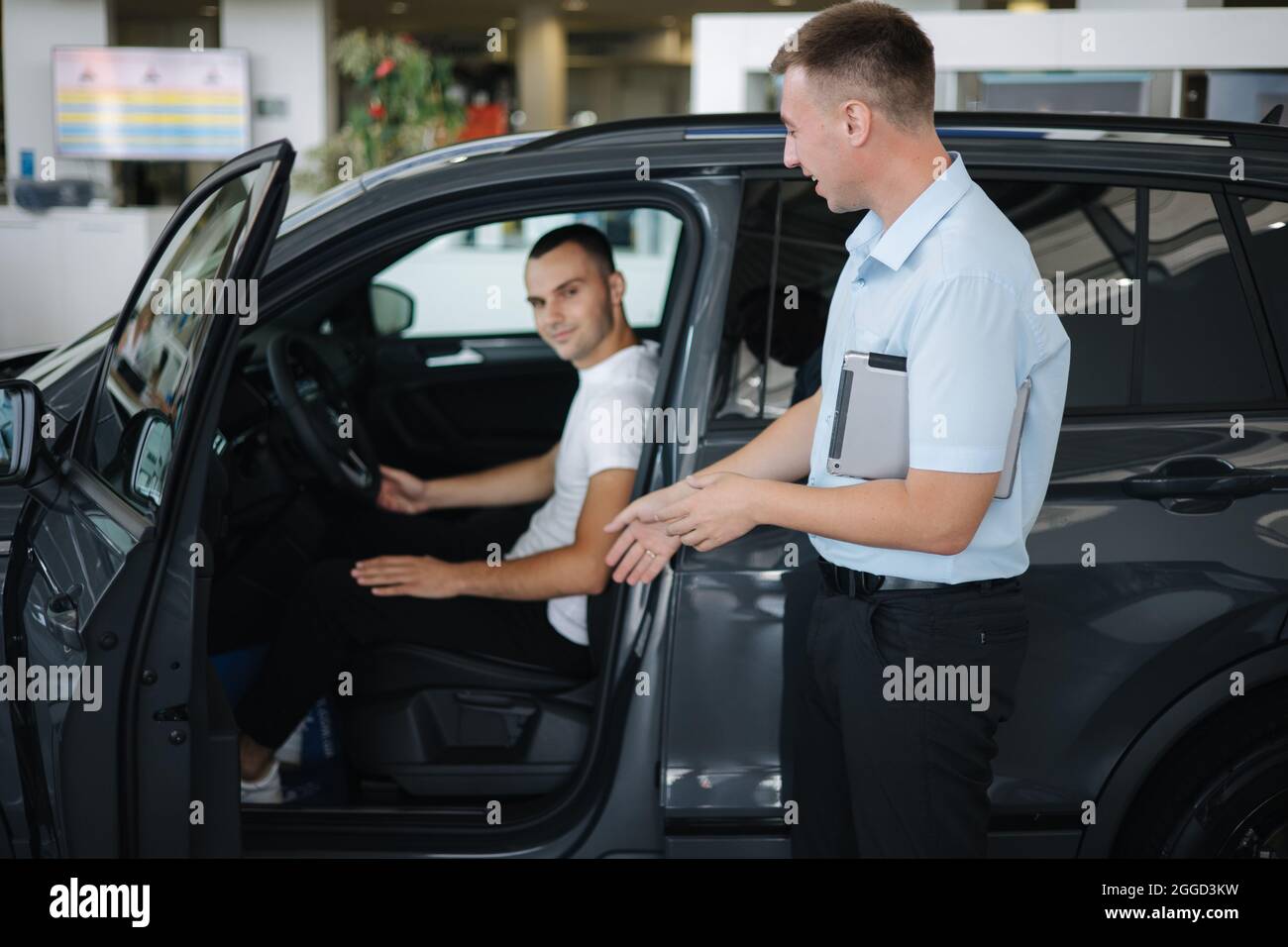 Salesperson selling cars at car dealership. Man choosing car in car ...