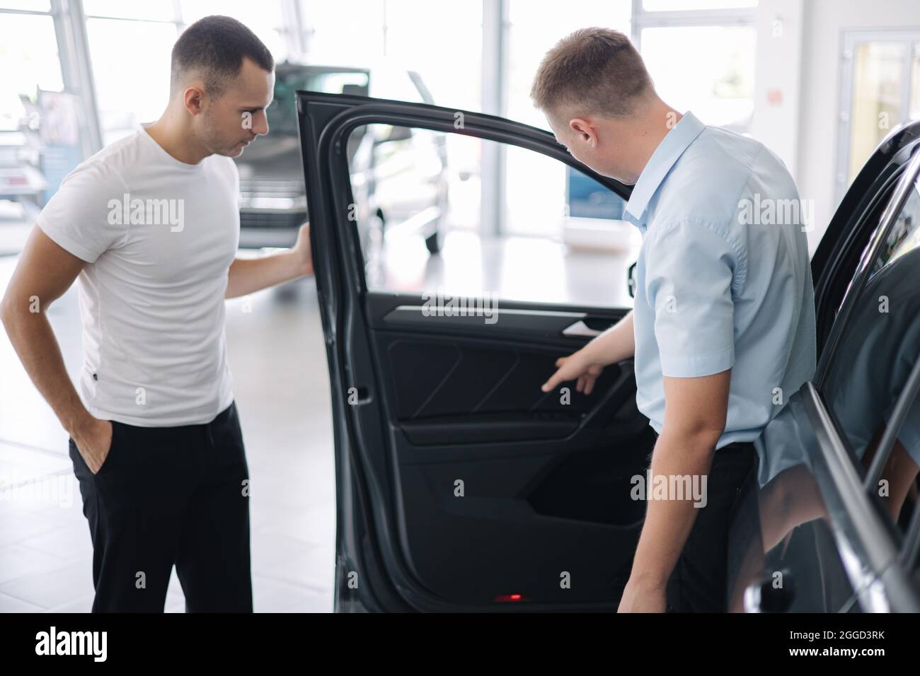 Salesperson selling cars at car dealership. Man choosing car in car ...