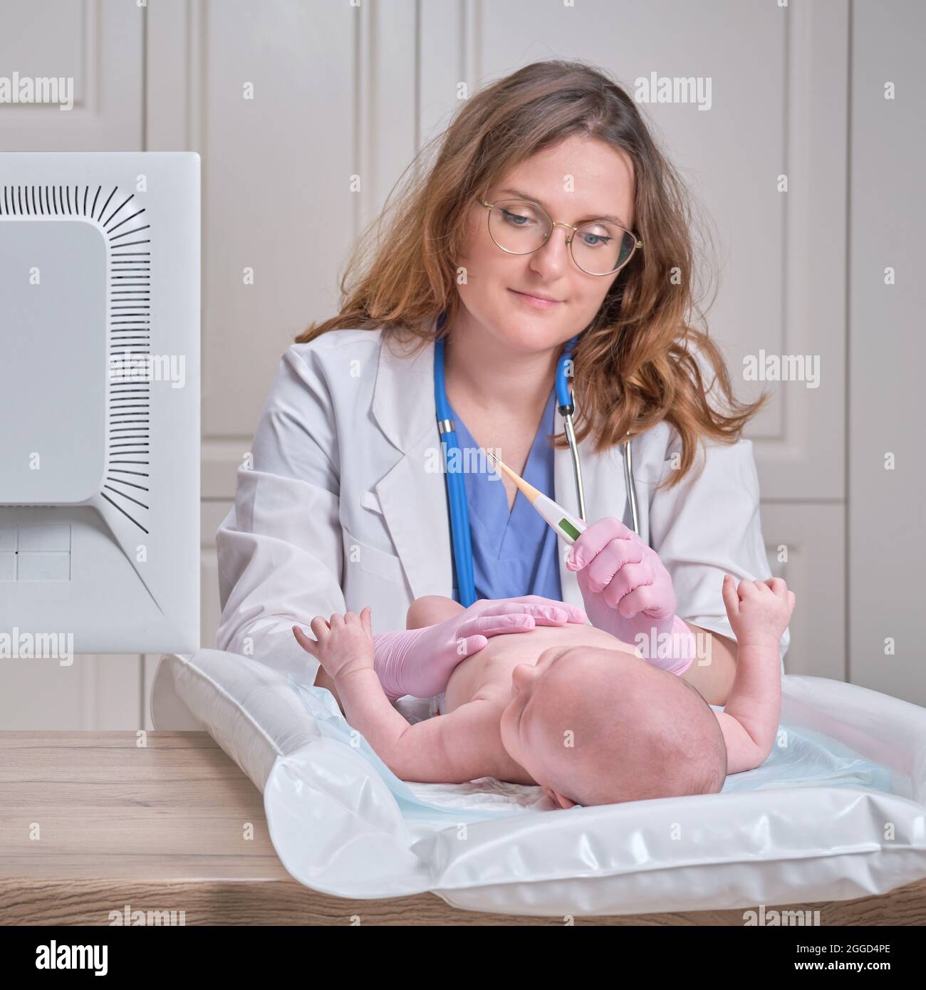 Doctor checks the temperature of the newborn baby with a thermometer. A ...
