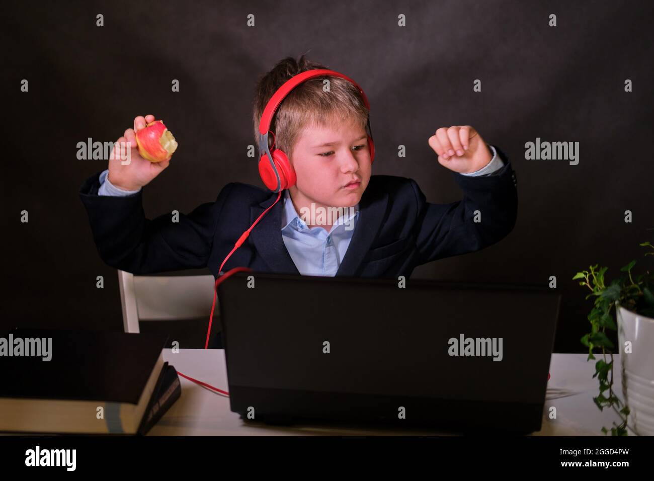 A happy boy in a school suit with headphones listens to music at the ...