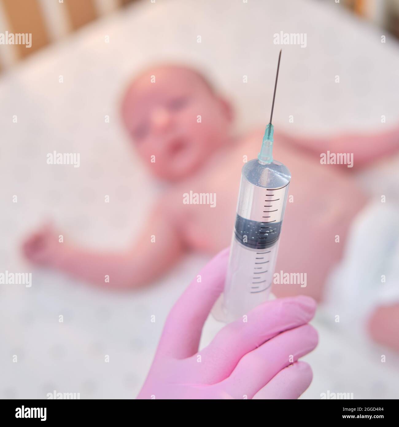 The doctor uses a syringe to inject a newborn child. A nurse in uniform ...