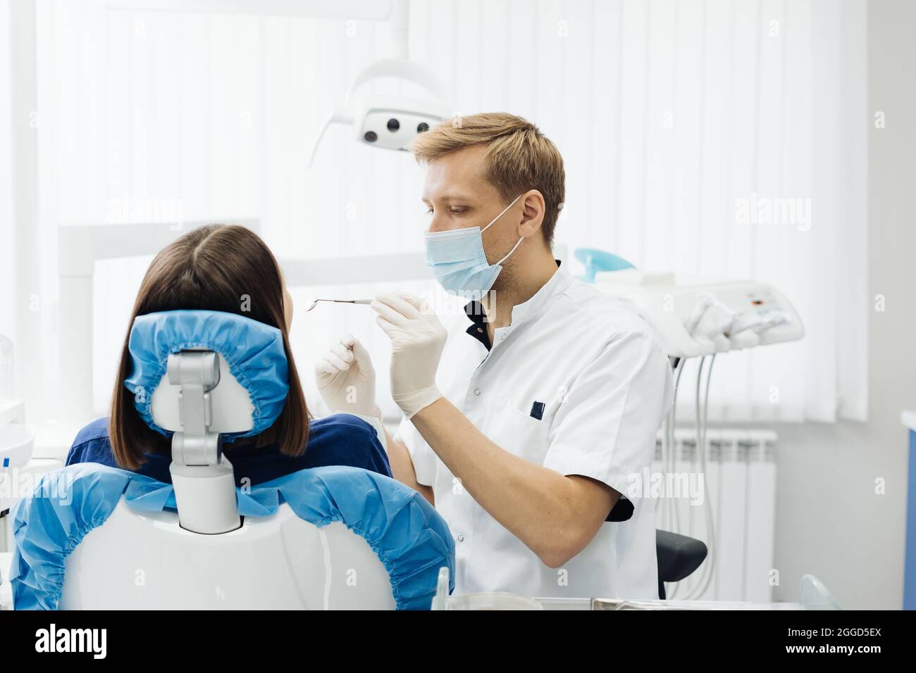 Caucasian male dentist examining young woman patient's teeth at dental ...