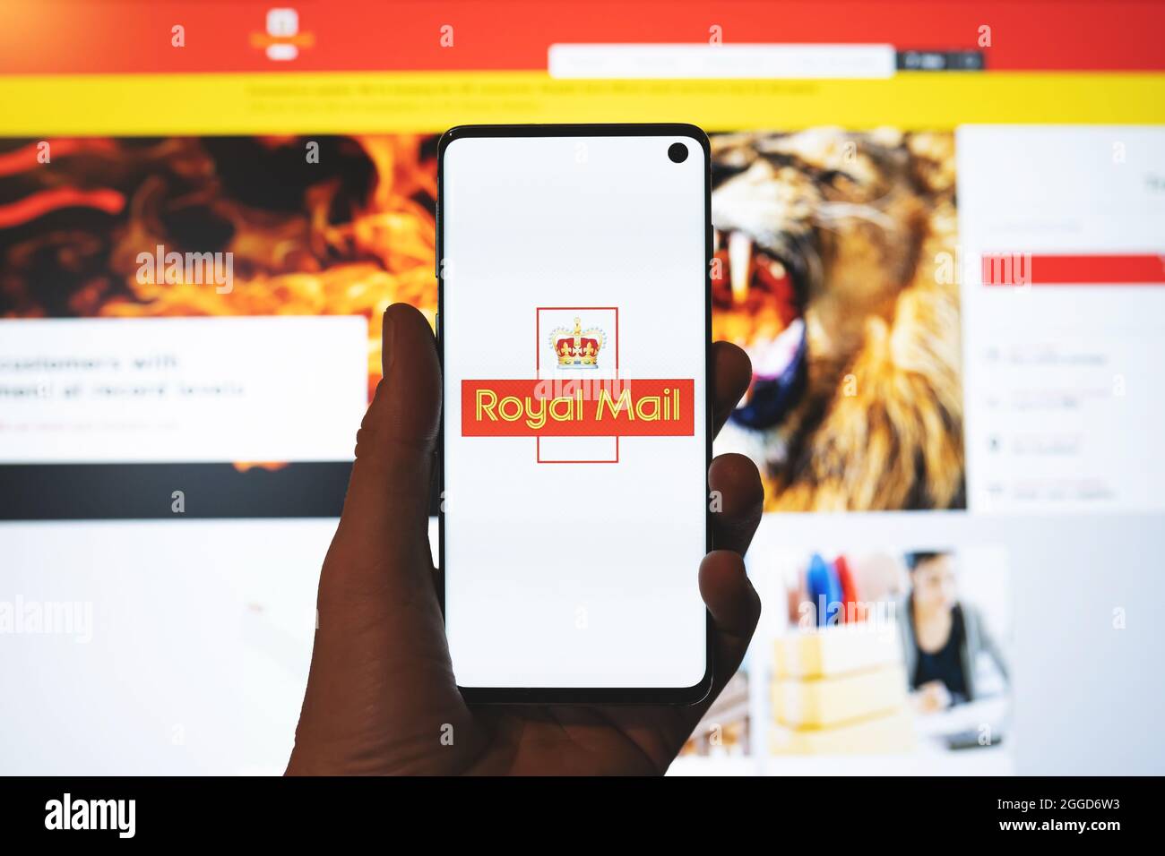 Royal Mail logo on smartphone in hand with blurred website background ...