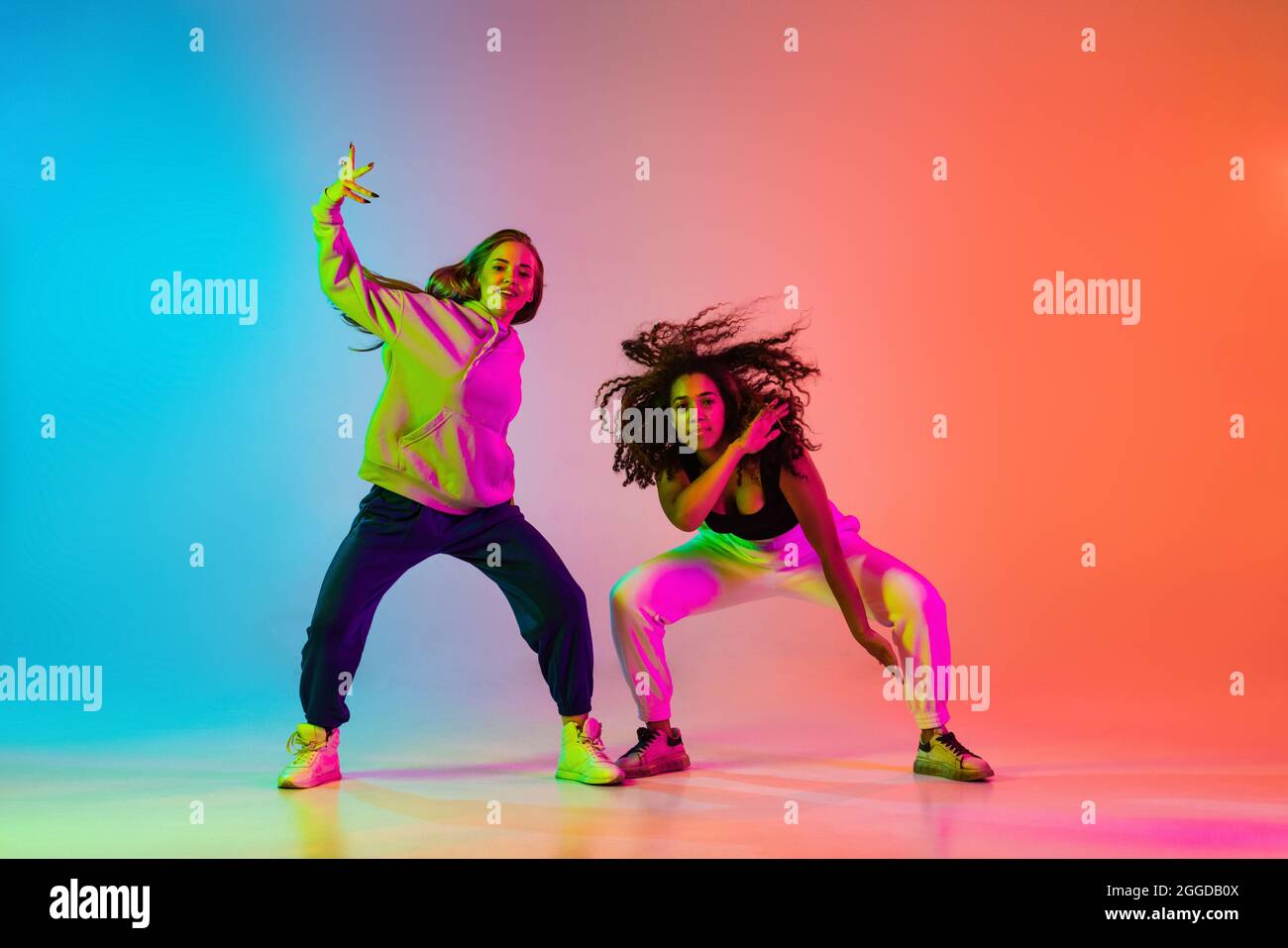 Two beautiful stylish hip-hop dancers on colorful gradient background ...