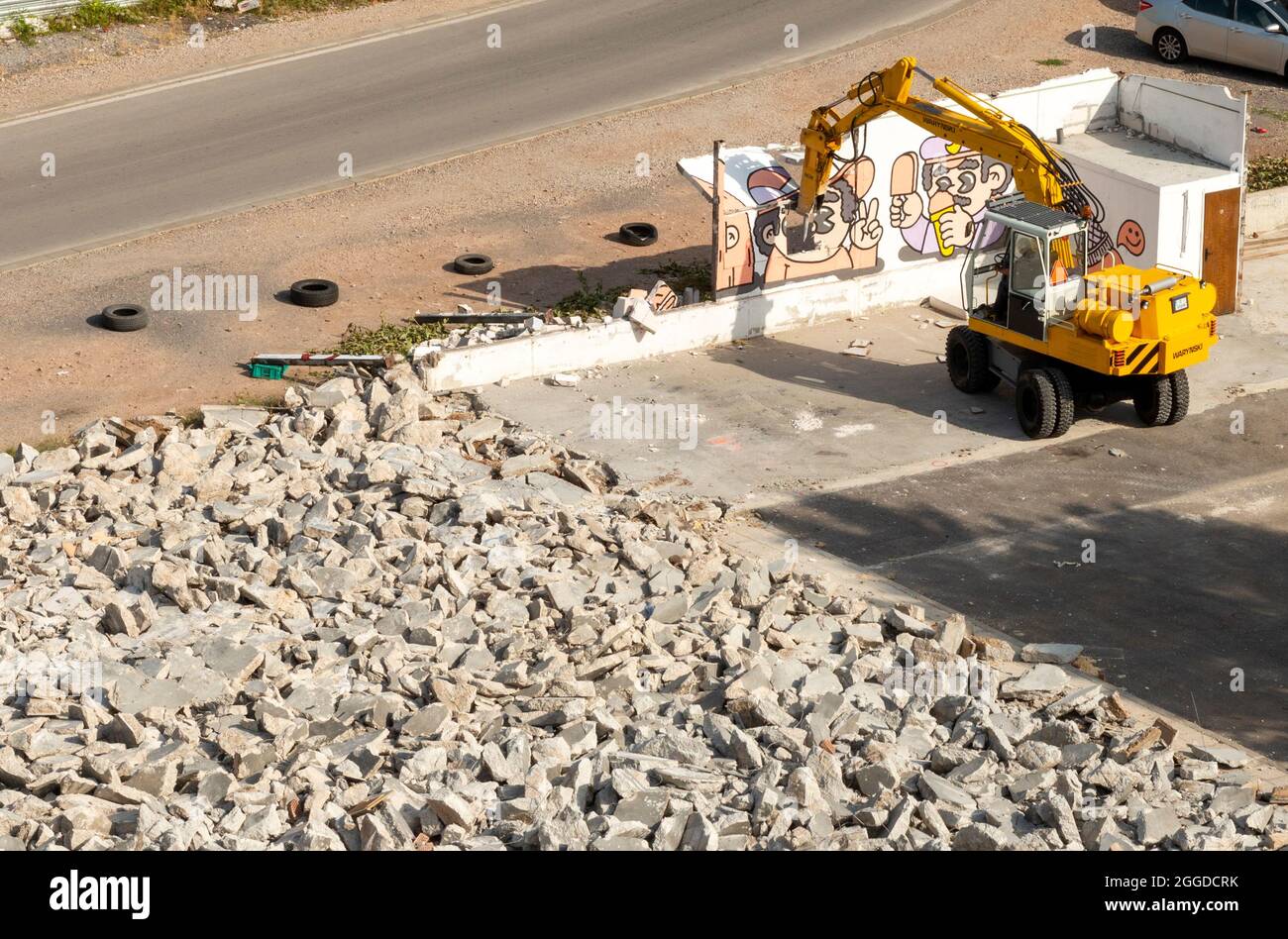 Building demolition digger demolishing a graffiti painted wall while ...