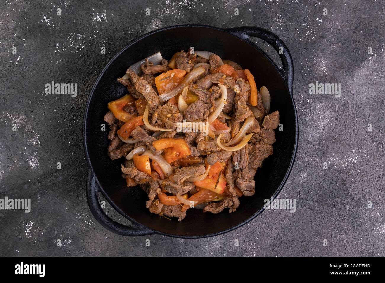 Sliced and fried filet mignon with tomato and onion in an iron skillet ...