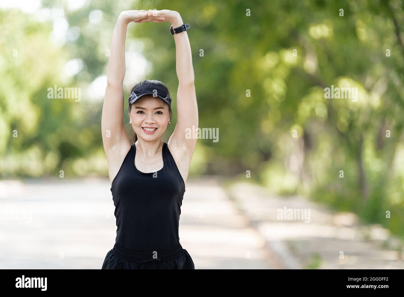 Cheerful Southeast Asian female runner in sports attire do some ...