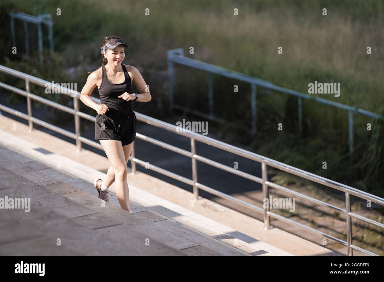 Southeast Asian female runner in black sports attire jogging in the ...