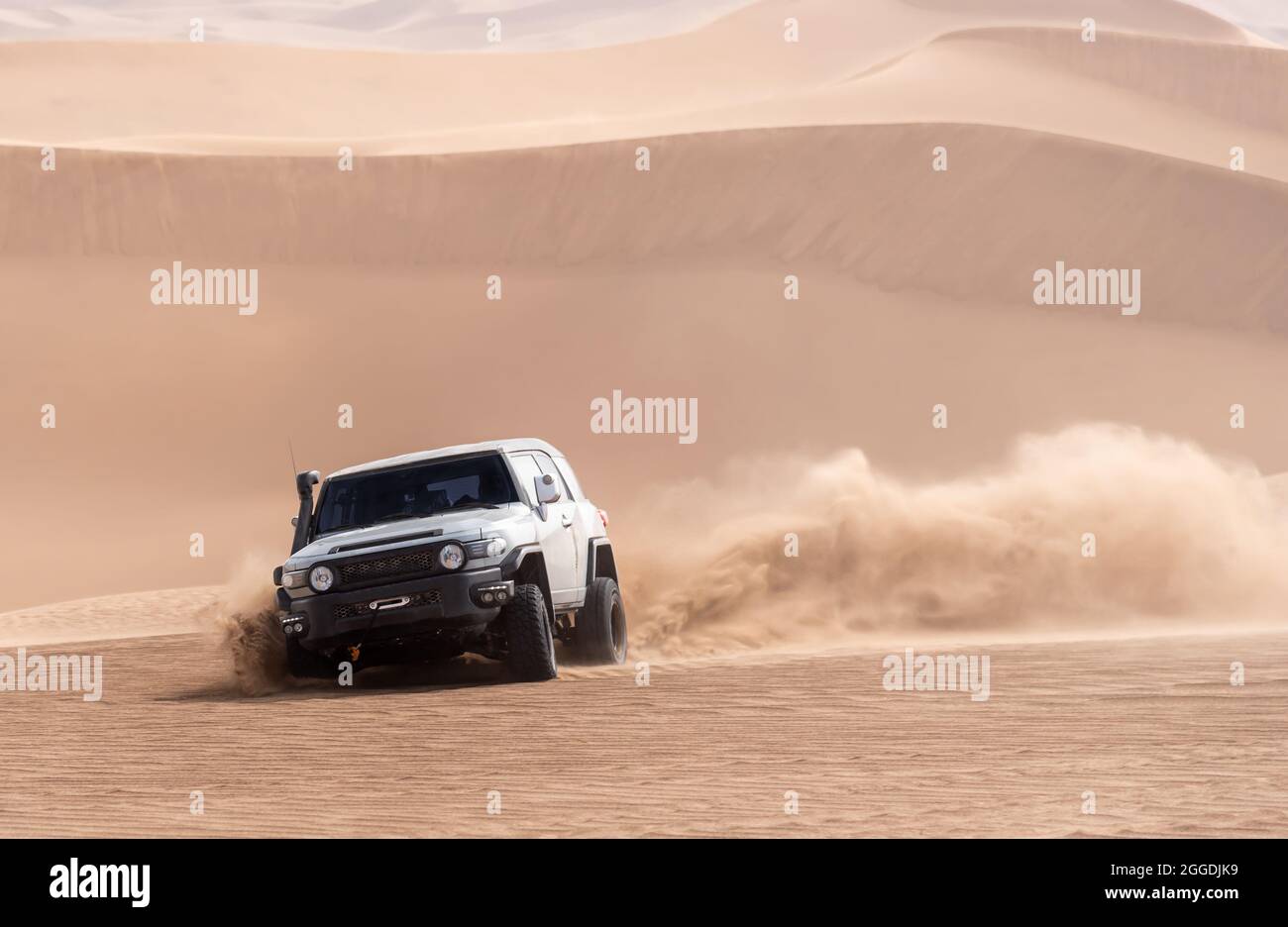 a car or suv is drifting an sands and splashing sands on air and around ...