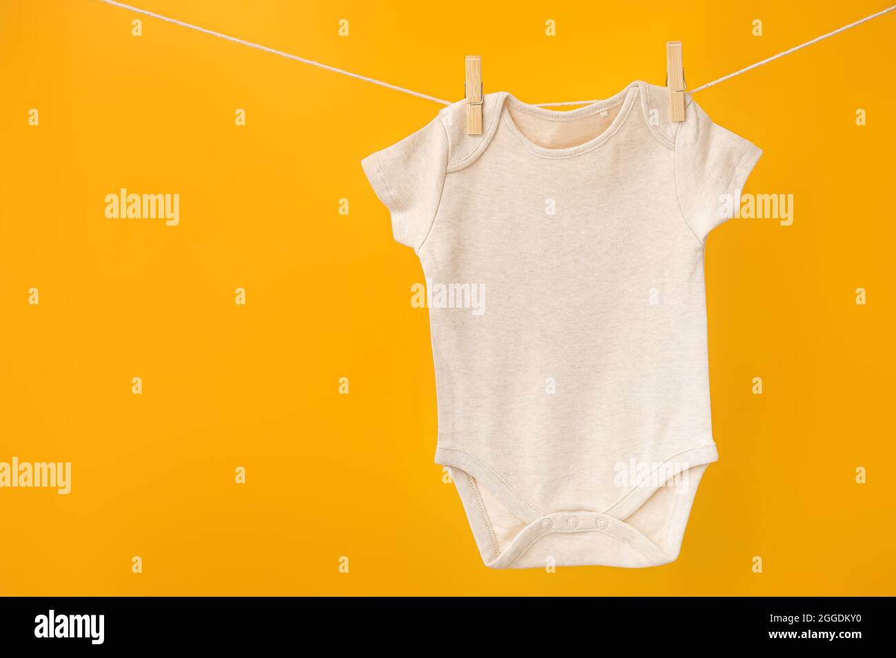 Baby clothes hanging on rope against color background Stock Photo - Alamy