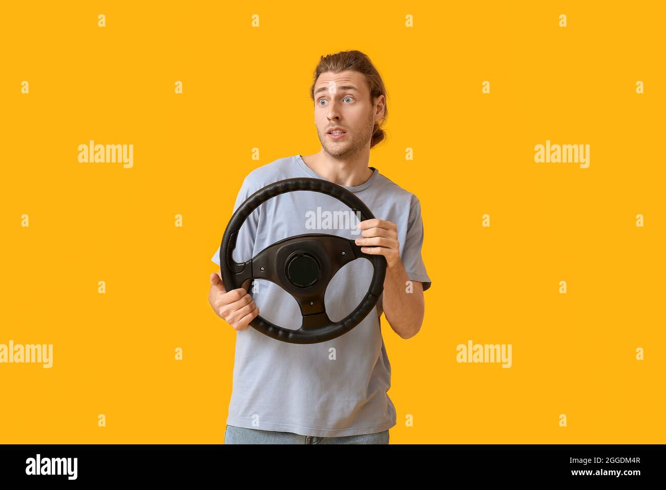 Shocked young man with steering wheel on color background Stock Photo ...