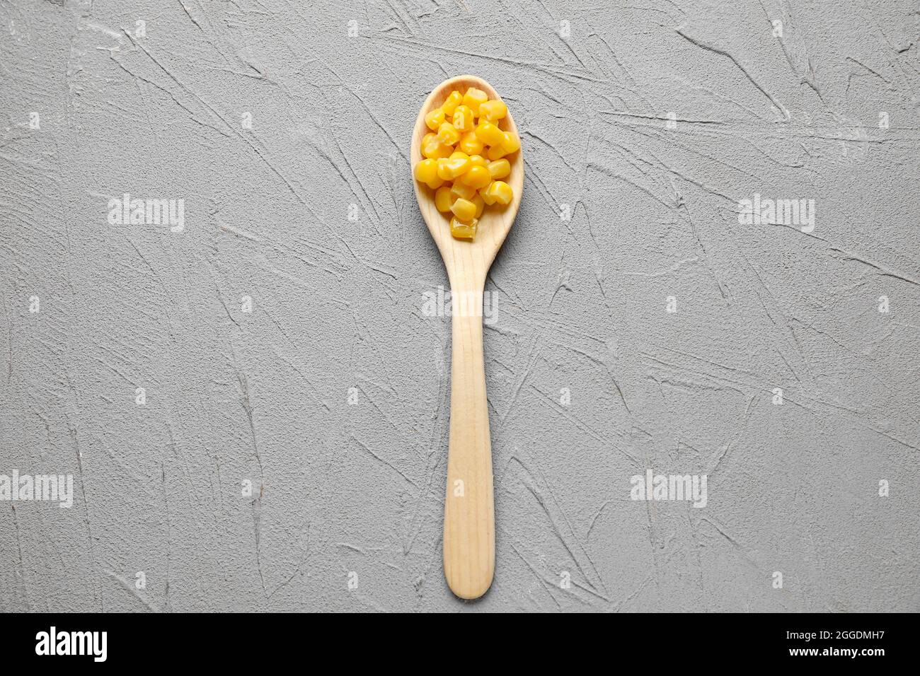 Spoon with corn kernels on grey background Stock Photo - Alamy