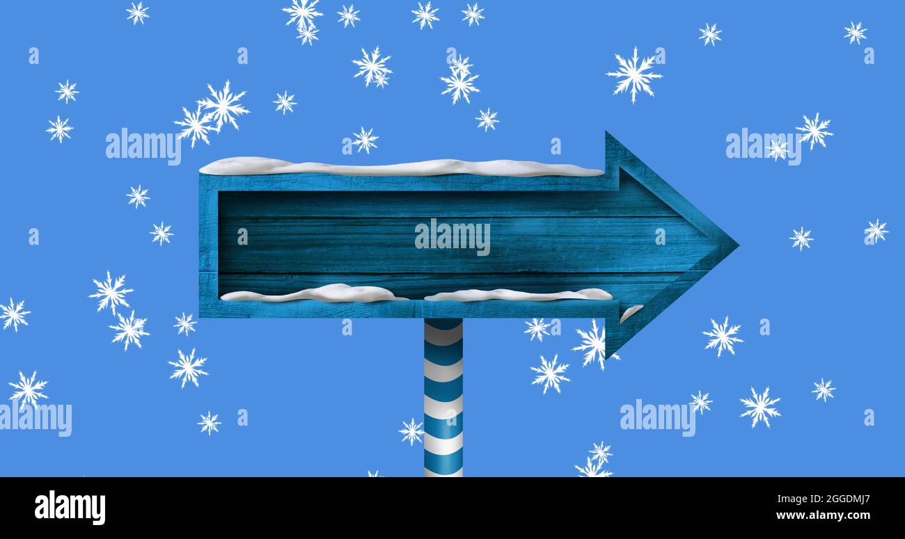 Digital image of snowflakes falling over blue wooden arrow shaped sign ...
