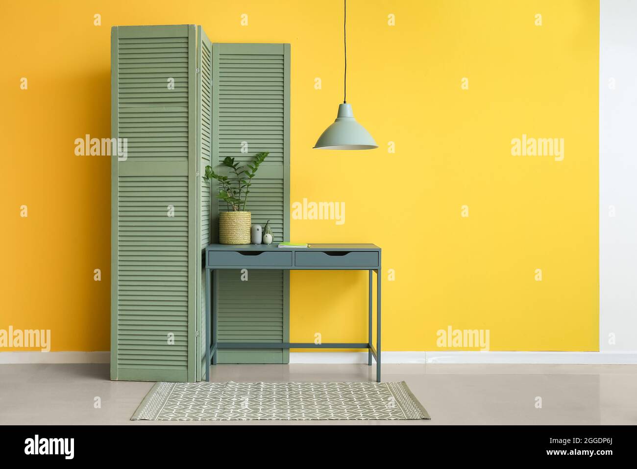 Modern workplace with folding screen near color wall Stock Photo - Alamy