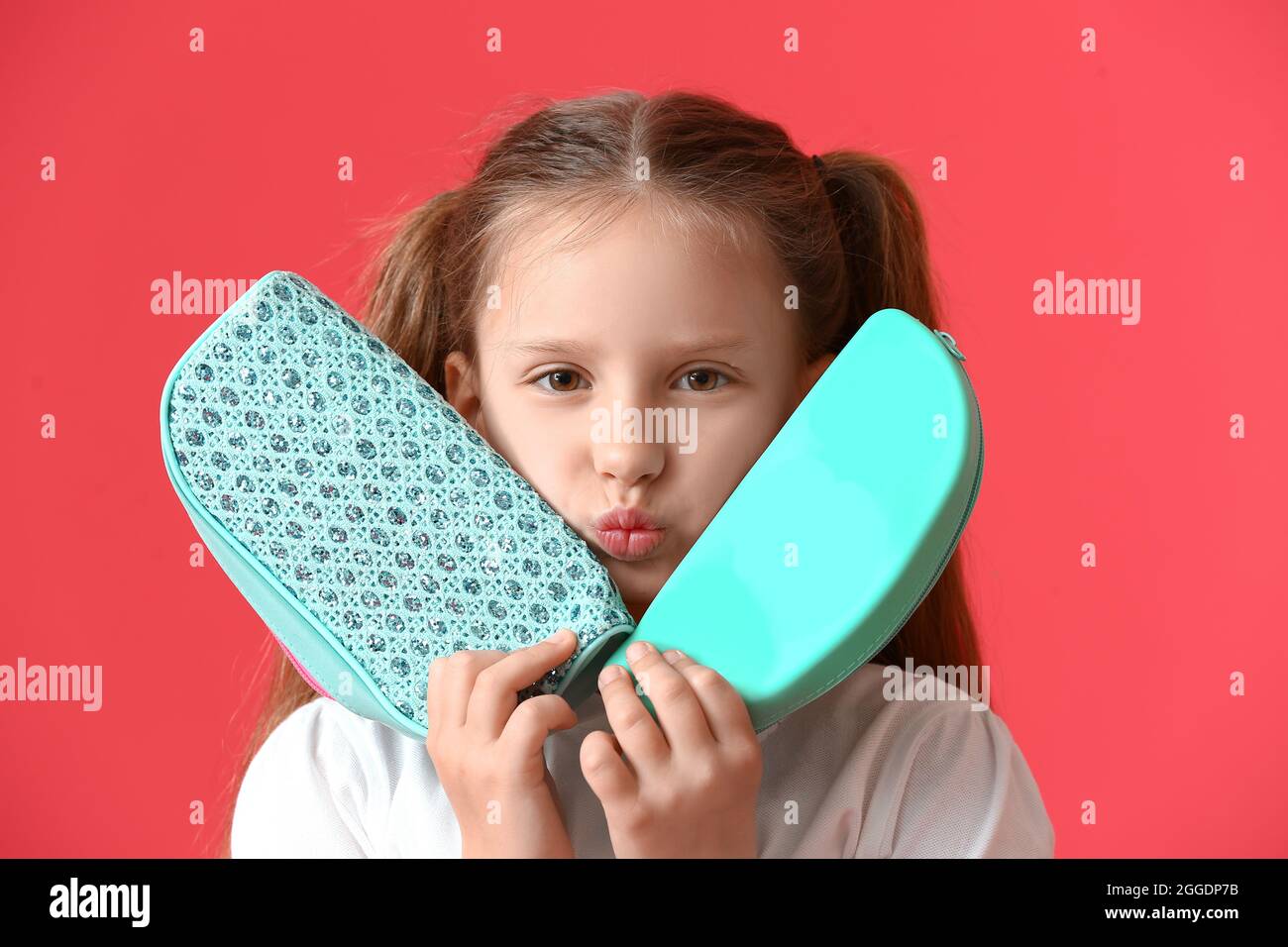 Little girl with pencil cases on color background Stock Photo - Alamy