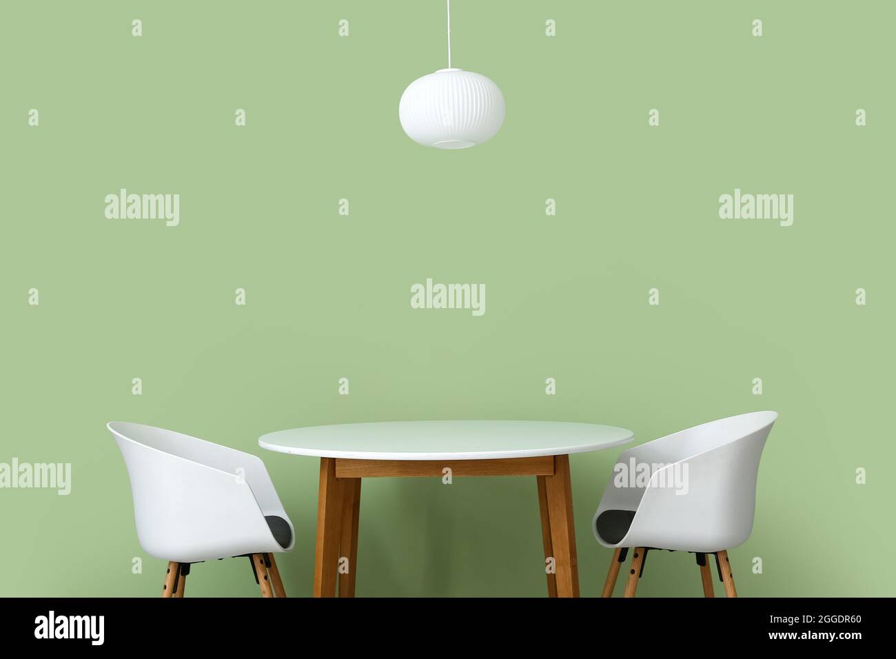 Stylish dining table near color wall Stock Photo - Alamy