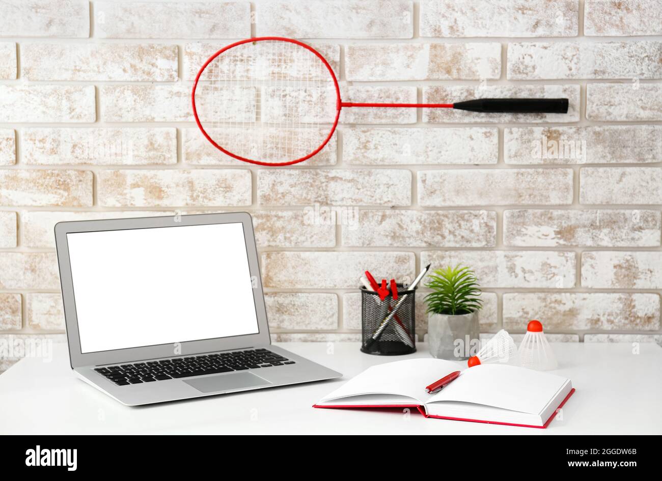 Laptop, badminton racket and shuttlecocks on table in office Stock ...