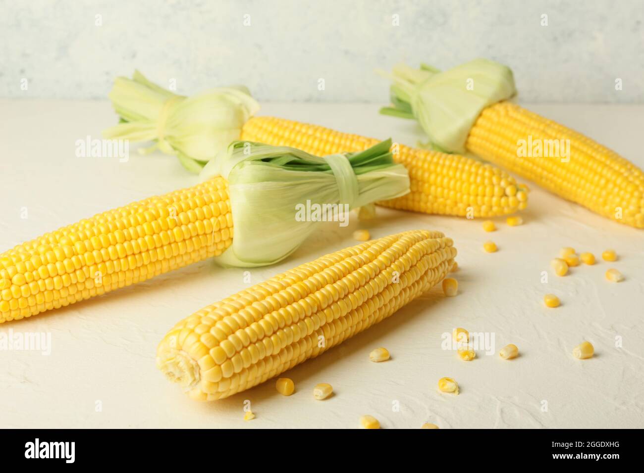 Fresh corn cobs on light background Stock Photo - Alamy