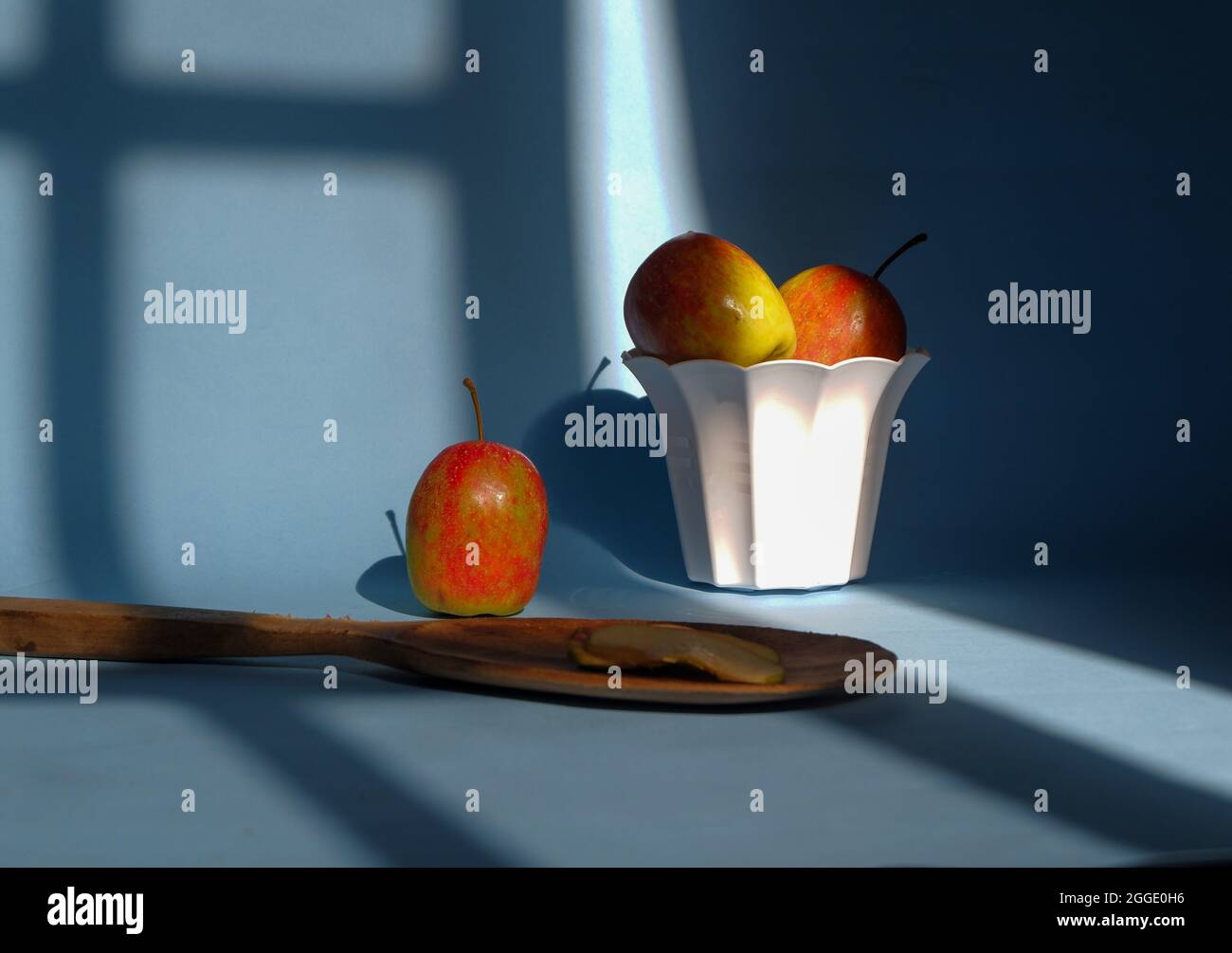 Split apple and a vase filled with apples on a blue background - still ...