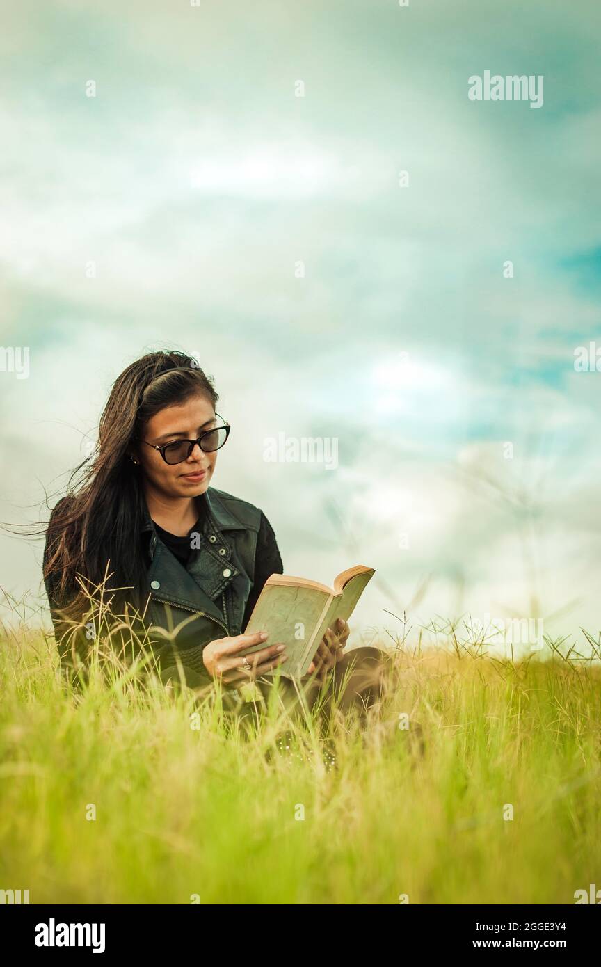 Woman reading in the field, girl reading a book with copy space El ...