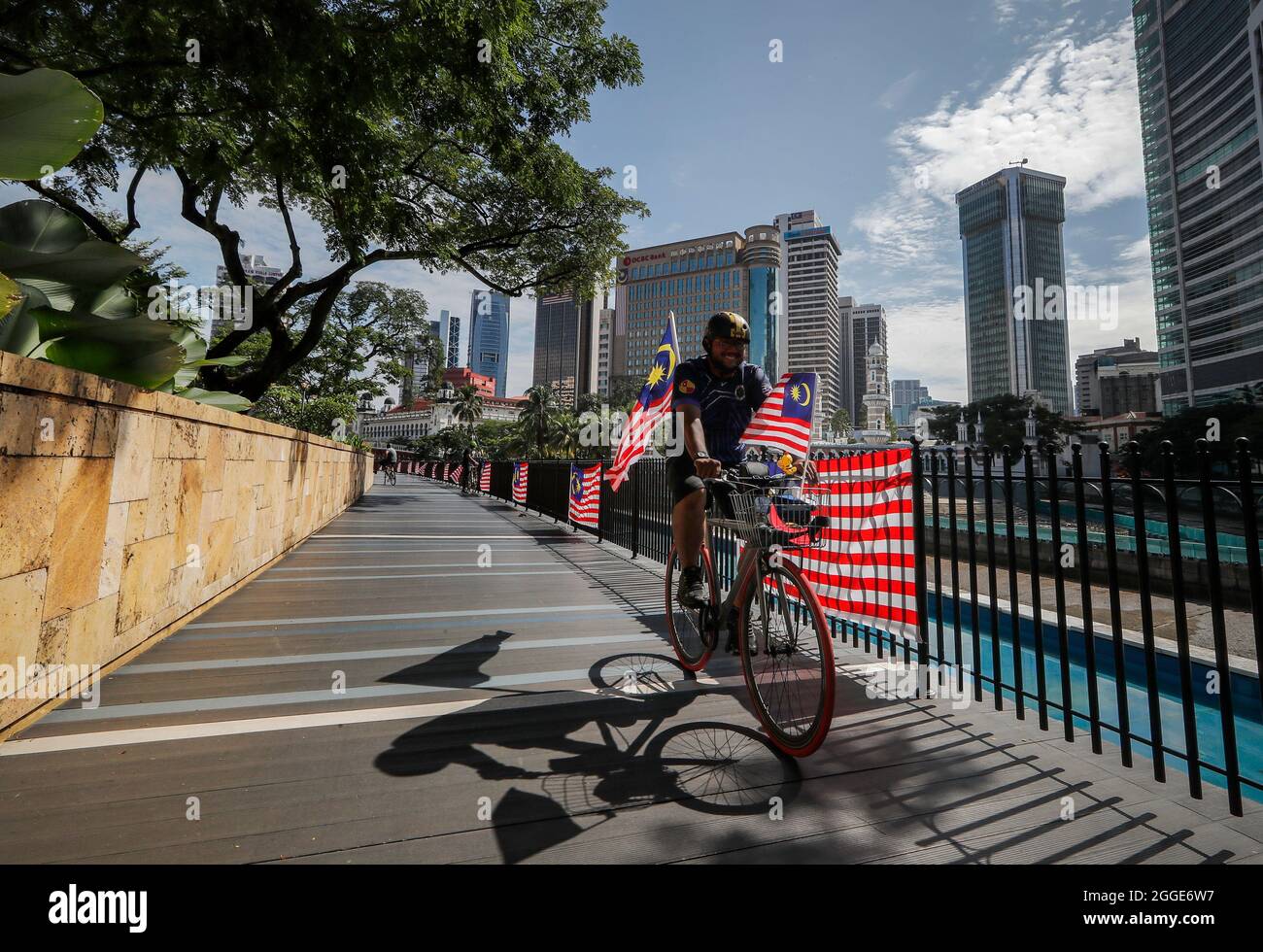 A cyclist rides past a Malaysian flag during the 64th National Day ...