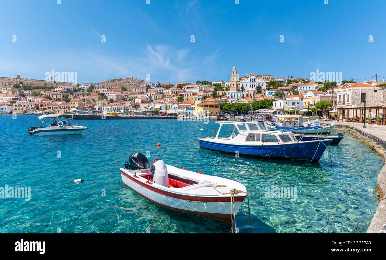 Fishing boats in the harbour of Halki with turquoise water, promenade ...
