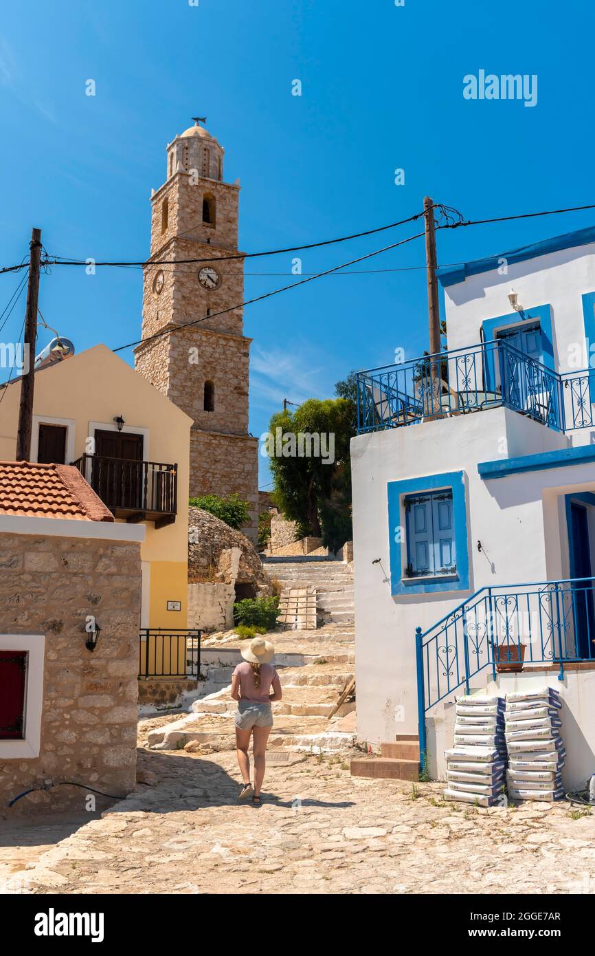 Tourist with sun hat, old town of Halki, Halki, Dodecanese, Greece ...