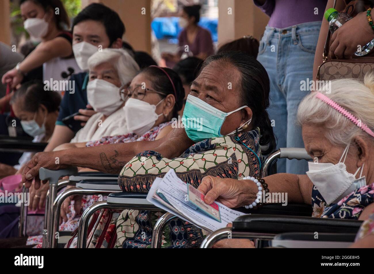 The elderly persons wearing face masks wait for their turn to receive ...