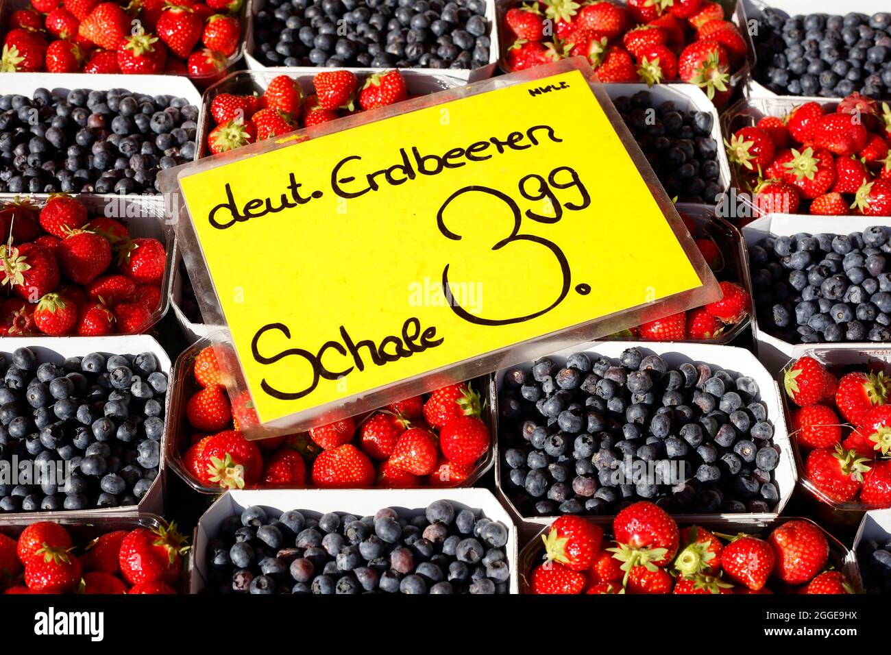 Fresh strawberries and blueberries in trays on a market stall, Bremen ...