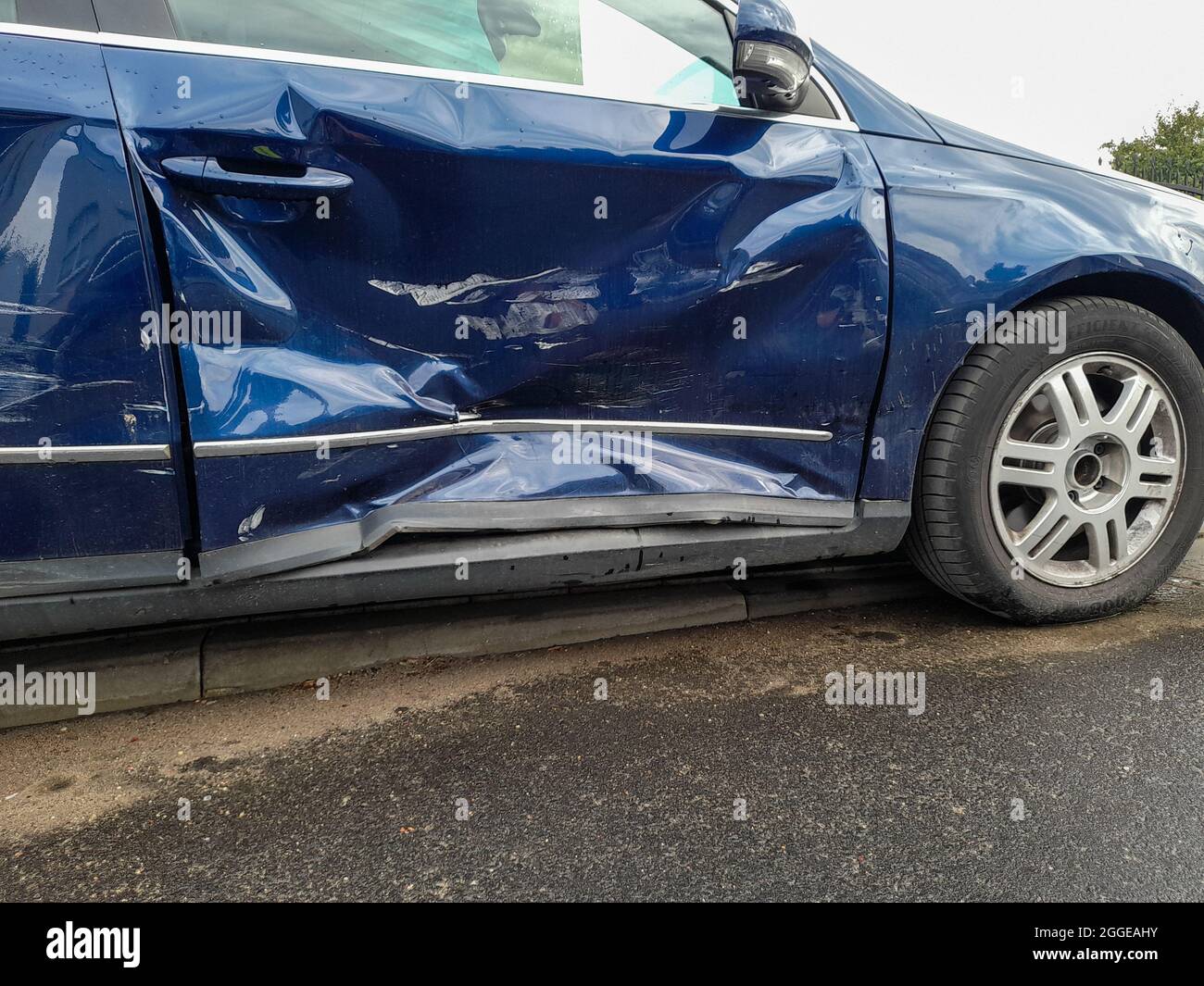 Closeup of a side door of a blue car damaged by an accident on the road ...
