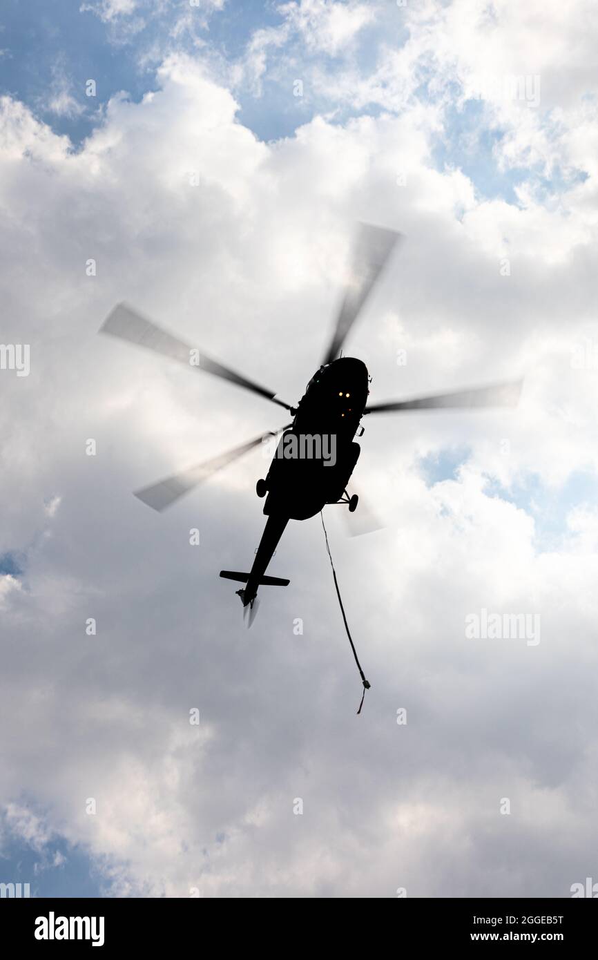 Silhouetted flying helicopter with blurry moving propeller and carrying ...
