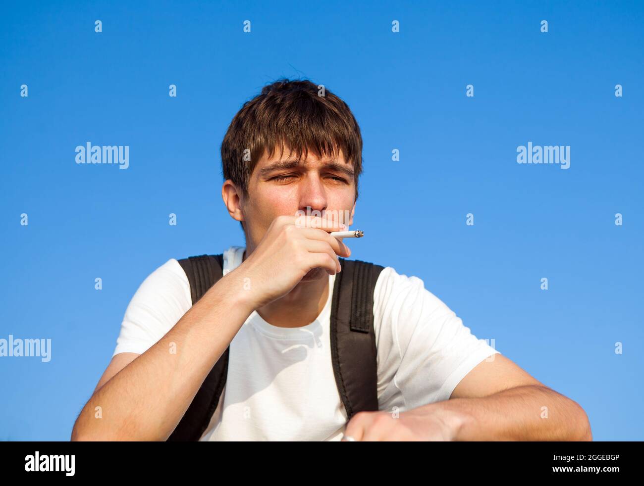 Sad Young Man smoking Cigarette on the Sky Background Stock Photo - Alamy