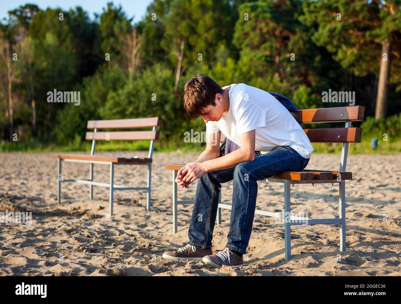 Sad Young Man sit on the Bench outdoor Stock Photo - Alamy